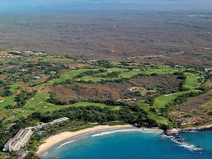 Lush green golf courses meet rugged coastline where Honokaʻa's beauty unfolds between mountain and sea.