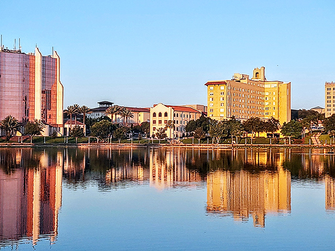 Lakeland's waterfront buildings reflect in mirror-like waters at sunset, offering scenic beauty that doesn't require a millionaire's budget.