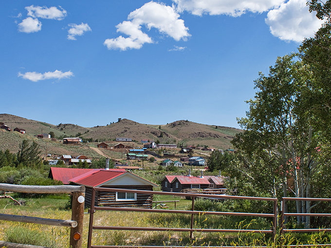 Historic Wyoming town nestled in rolling hills under a brilliant blue sky with scattered clouds.