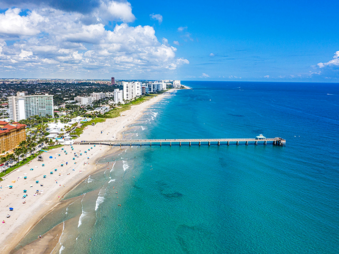 The famous pier extends into crystal-clear waters while beachgoers enjoy the wide sandy shores of this delightful coastal community.