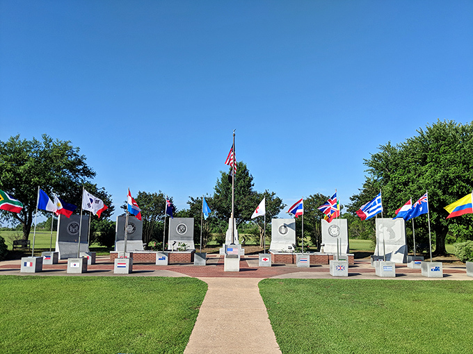 The Alabama Korean War Memorial stands solemn under a perfect sky, flags dancing in Gulf breezes as visitors reflect on sacrifices made.