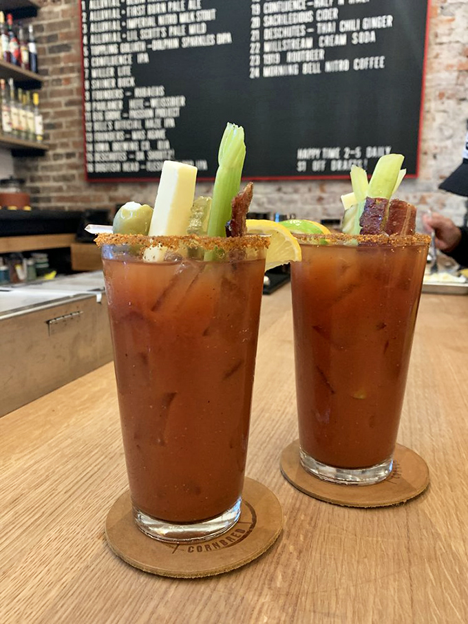 Bloody Marys garnished with celery, cheese, and what appears to be bacon&mdash;because at Cornbred, even the drinks come with a side of protein.