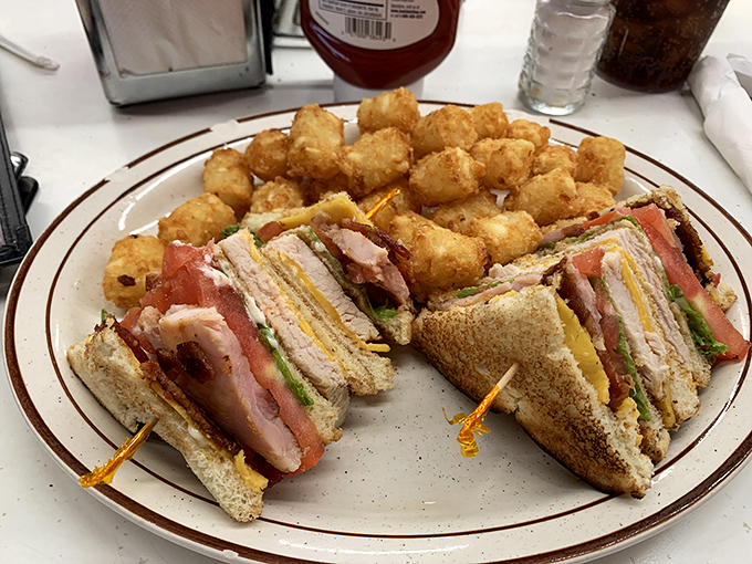 This club sandwich stands taller than most small buildings. A skyscraper of flavor that requires strategic eating techniques.