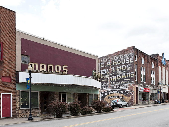 The vintage Manos Theatre marquee shares wall space with ghost signs advertising pianos and organs&mdash;a visual time capsule of small-town entertainment evolution.