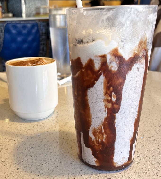 A chocolate milkshake so thick it laughs at your straw's feeble attempts to transport it, sitting proudly next to coffee that means business.