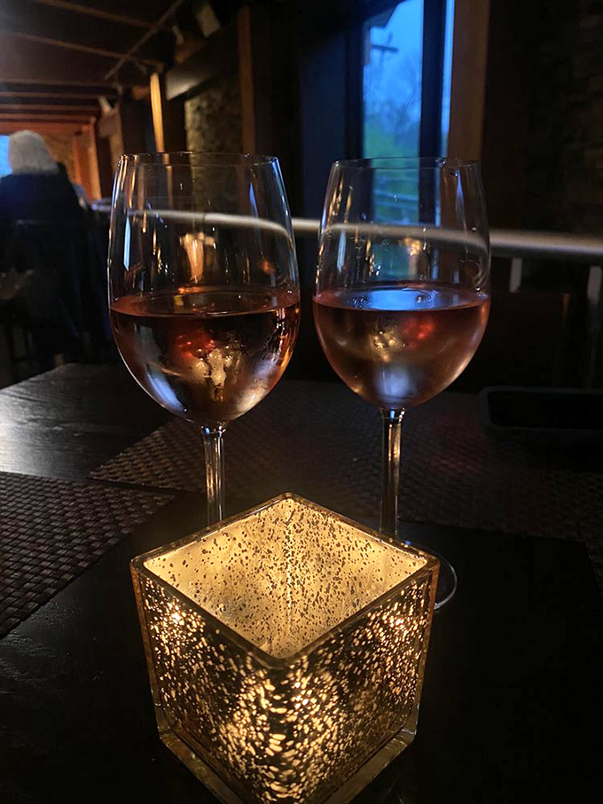Two glasses of ros&eacute; catching the light, with a glowing table candle creating that "this is definitely not just another Tuesday" ambiance.
