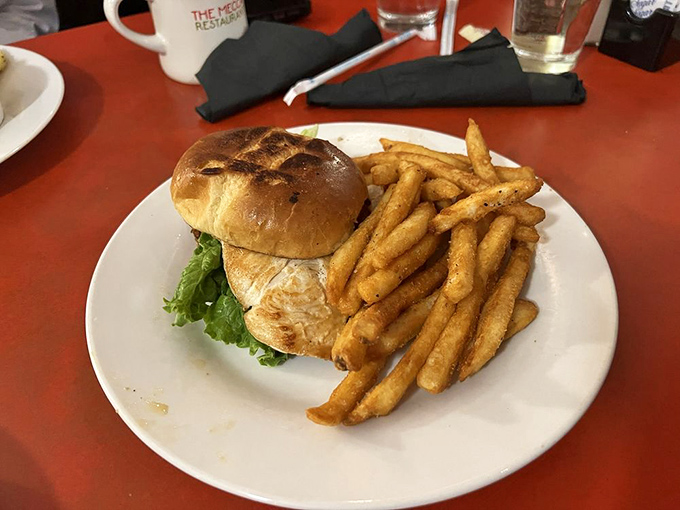 A sandwich that requires both hands and your full attention, paired with golden fries that could make a potato proud.