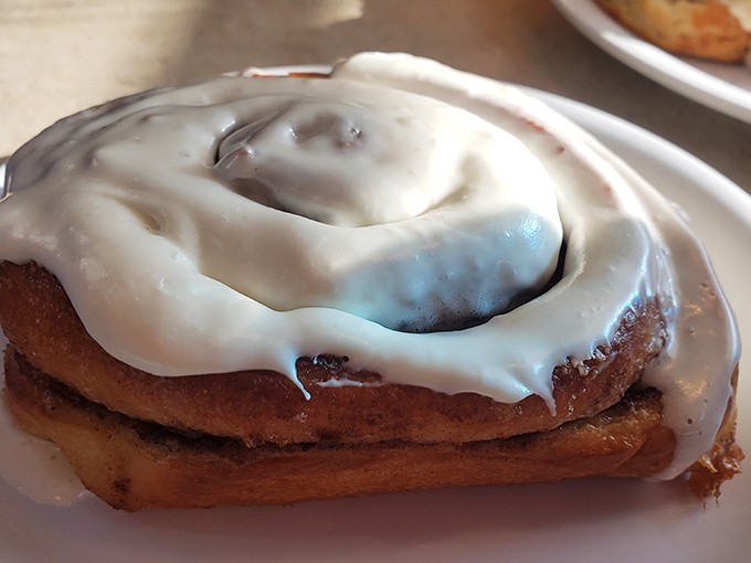 A cinnamon roll that's not messing around—frosted with such abandon it makes you wonder if the baker was feeling particularly generous that day.