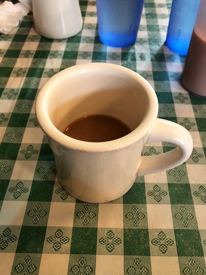 This isn't just coffee&mdash;it's morning salvation in ceramic form, sitting patiently on that iconic green checkered tablecloth waiting to change your day.