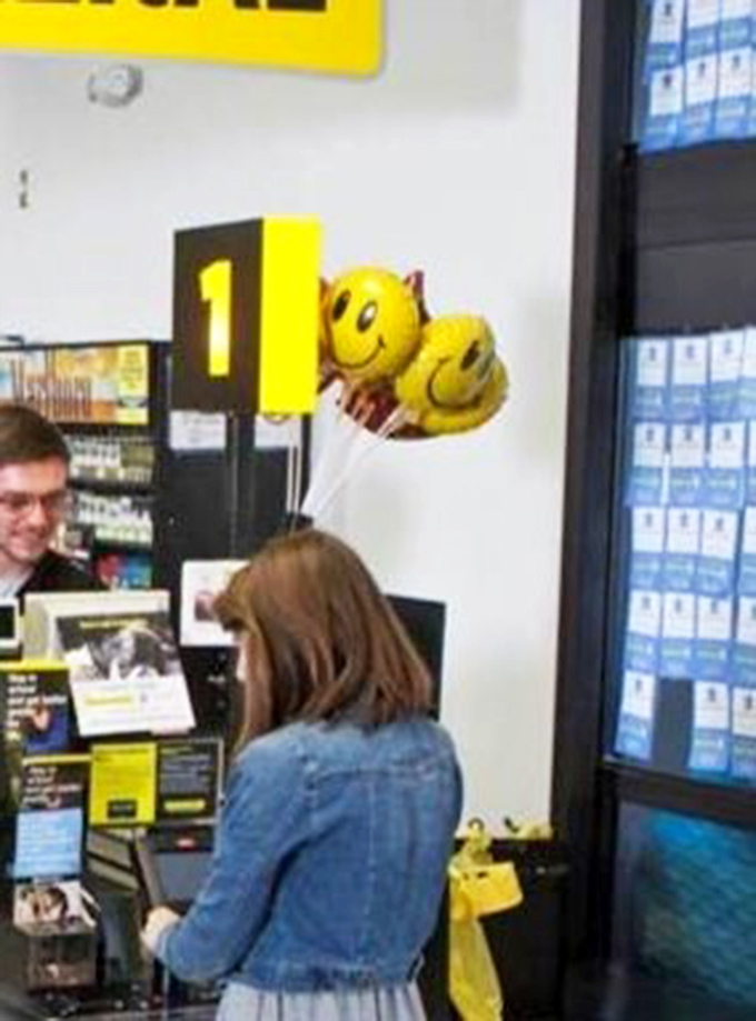 A friendly transaction in progress, where yellow smiley balloons mirror the customer service experience that keeps Batesville shoppers coming back.