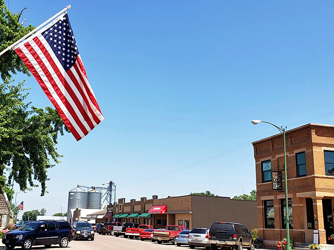 A proud American flag waves over Freeman's Main Street, where brick buildings and grain elevators define the town's character.