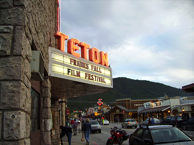 The historic Teton Theatre marquee lights up Jackson's evening scene, where mountain town charm meets cultural sophistication without losing its Western soul.