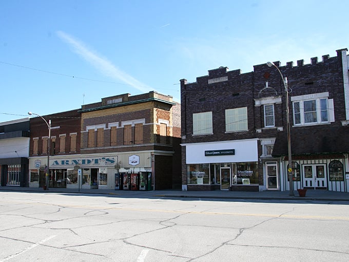 Historic storefronts line Olney's main street, where Arvin's shop has served generations of locals under bright blue skies.