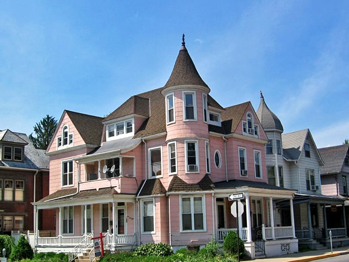 Historic pink Victorian home in Sunbury showcases charming turrets and wrap-around porch against blue skies.