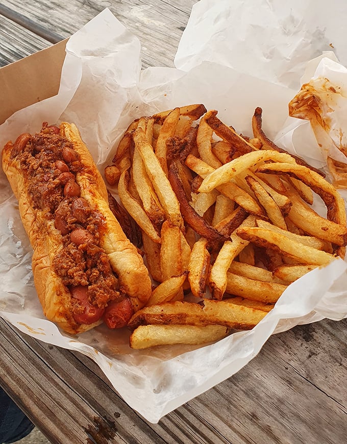 The chili dog and fries combo—proof that sometimes the most perfect meals come in humble paper containers on weathered picnic tables.