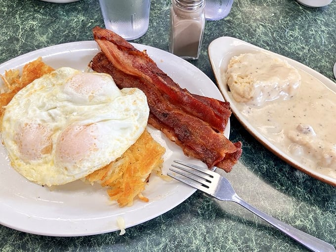 Breakfast perfection: crispy bacon, eggs with sunshine-yellow yolks, and a side of country gravy that could make cardboard taste good.