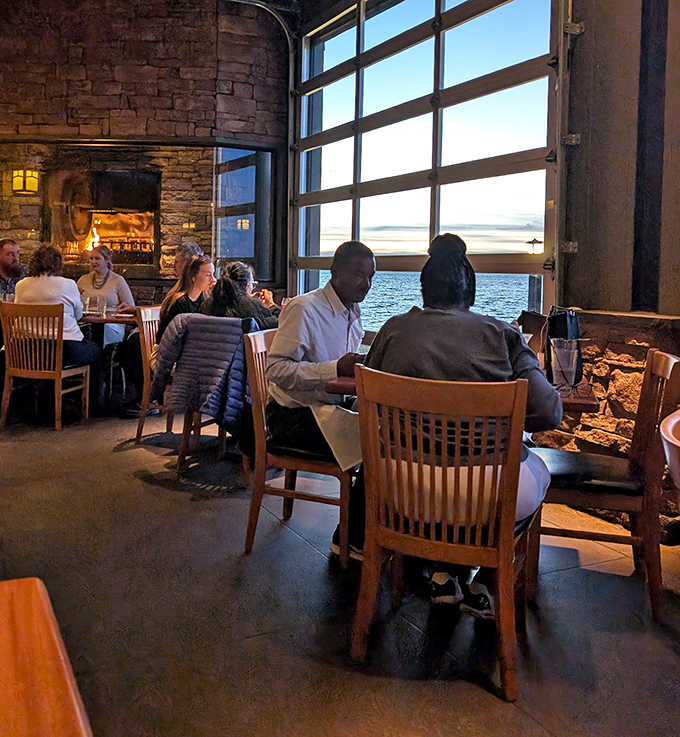 Diners bask in the glow of sunset through massive windows, proving food always tastes better with a view.