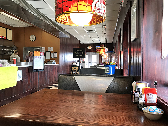 Stained glass pendant lights cast a warm glow over wooden booths where strangers become friends and diet plans go to die.