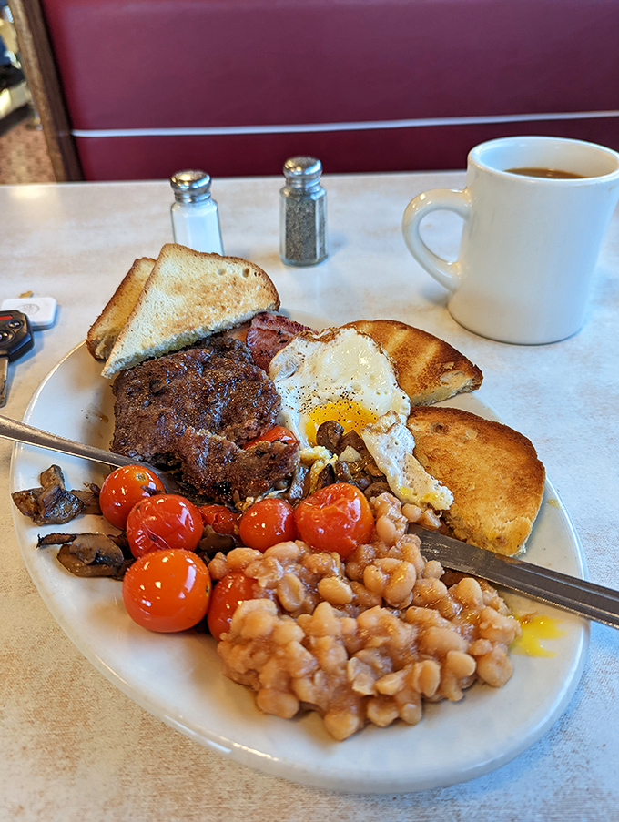 The full English breakfast experience: A symphony of savory delights featuring baked beans, roasted tomatoes, and toast that's ready to soak up every last bit of egg yolk.