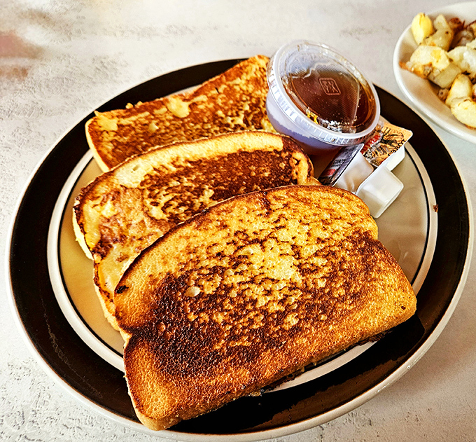 French toast with the perfect golden-brown crust—crispy edges, custardy center, and enough maple syrup to make a Canadian blush.