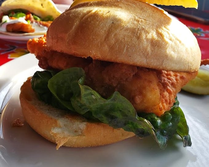 A sandwich that demands two hands and your full attention. Crispy fried fish nestled in a pillowy bun with fresh greens &ndash; simplicity at its finest.