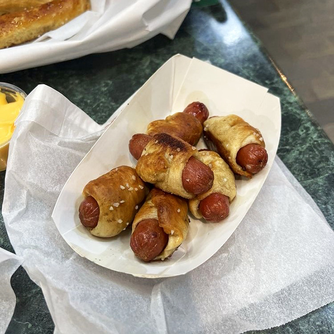 Pigs in pretzel blankets looking absolutely adorable and completely irresistible on their little serving plate.