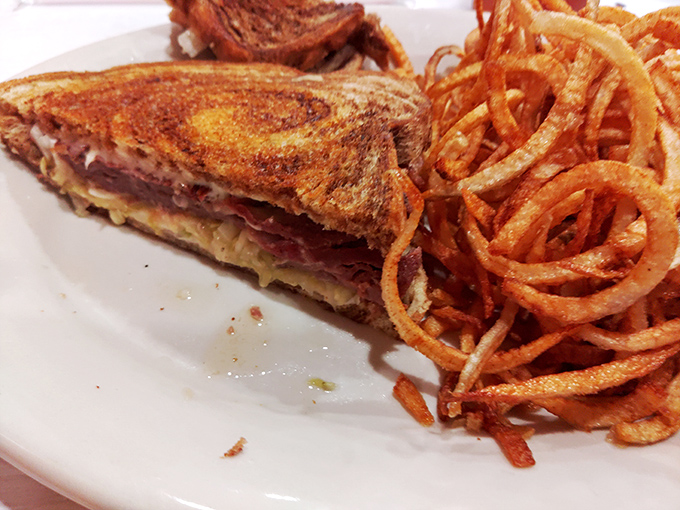 This isn't just a sandwich; it's architecture&mdash;perfectly grilled bread supporting layers of flavor, with curly fries standing guard.