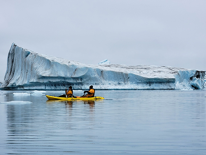 Kayakers paddle past an iceberg the size of a house, gaining perspective on just how small we humans really are.