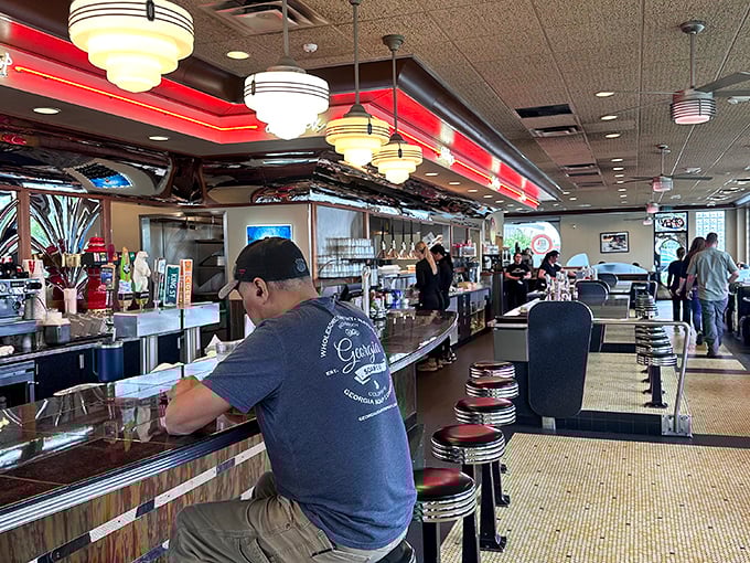 Classic diner perfection where pendant lights cast that magical glow making everyone look like they're starring in their own 1950s sitcom.