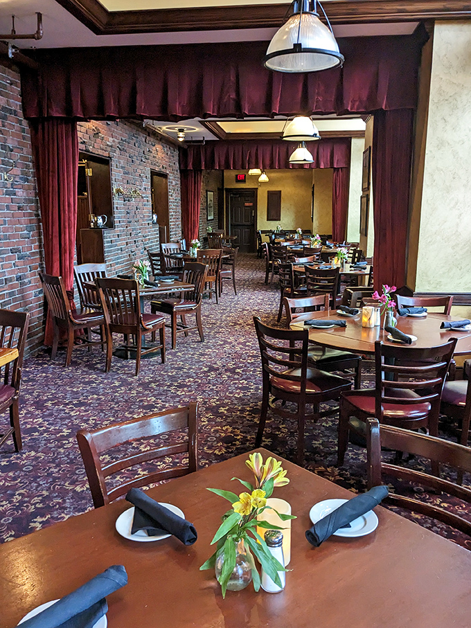 Burgundy curtains frame wooden tables where countless anniversary toasts and business deals have been sealed over decades.