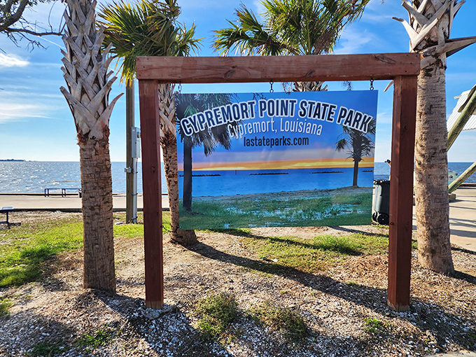 The park's entrance sign promises what lies beyond – a slice of coastal tranquility framed by palm trees and endless sky.