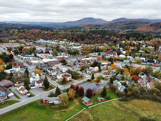 Lyndonville unfolds beneath mountain guardians, its neat grid of streets and colorful homes promising small-town magic without big-city prices.