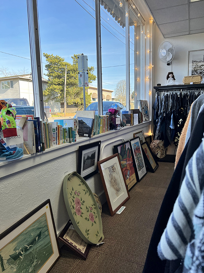 Sunlight streams through windows illuminating framed art and books. A quiet corner for contemplative thrifting &ndash; Thoreau would approve.