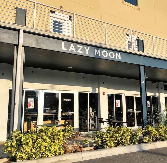 The blue awning of Lazy Moon beckons like a celestial invitation to pizza paradise, promising oversized slices and undersized bills.