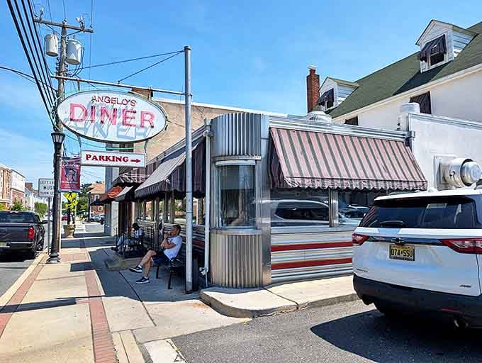 That iconic oval sign beckons like a lighthouse for hungry travelers. Angelo's stainless steel exterior and striped awnings are a portal to simpler, delicious times.
