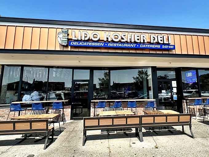 The iconic orange-paneled storefront of Lido Kosher Deli beckons with promises of sandwich nirvana. Those blue chairs have supported generations of happy, overstuffed customers.