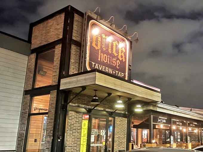 The illuminated Brick House Tavern + Tap sign glows invitingly against the night sky, beckoning hungry patrons to discover its comfort food treasures.