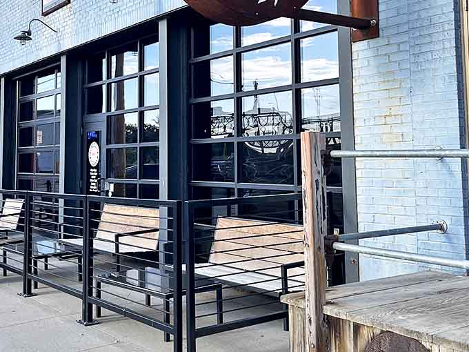 The inviting entrance of The Starving Rooster features rustic wooden benches and large windows that welcome hungry visitors to Minot.