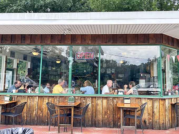 The outdoor seating area at Henry's Smokehouse invites you to linger over your barbecue while watching Greenville life unfold through glass-enclosed comfort.