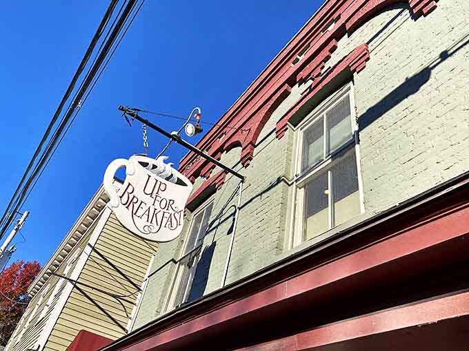 Against Vermont's brilliant blue autumn sky, the charming coffee cup sign swings gently in the breeze, promising morning salvation to those wise enough to climb those stairs.