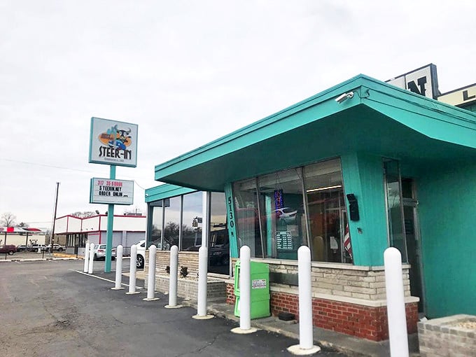 The iconic turquoise exterior of Steer-In welcomes hungry visitors with its vintage charm and distinctive white posts guarding the entrance.