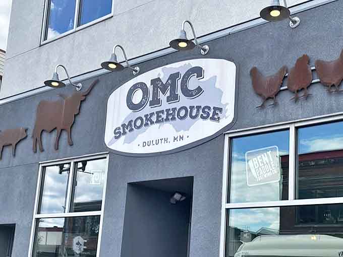 The iconic OMC Smokehouse sign with metal silhouettes of cattle and chickens—Oink, Moo, Cluck brought to life on Duluth's Lincoln Park streetscape.