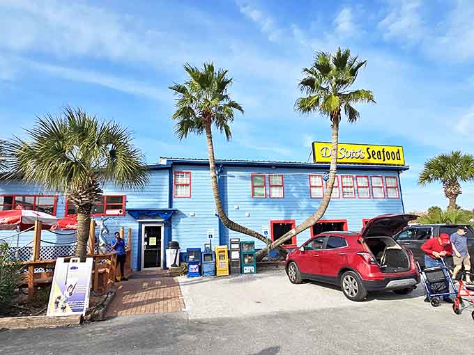 The iconic blue exterior of De Soto's Seafood Kitchen welcomes hungry visitors with swaying palm trees and Gulf Coast charm.