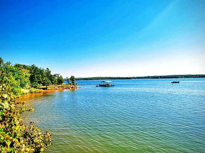 Mother Nature showing off her watercolor skills at Lake Thunderbird, where the shoreline curves like a smile and boats drift lazily under Oklahoma's impossibly blue sky.