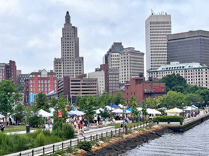 The iconic Providence skyline creates a stunning backdrop for the Flea Market's white tents lining the scenic riverfront greenway.