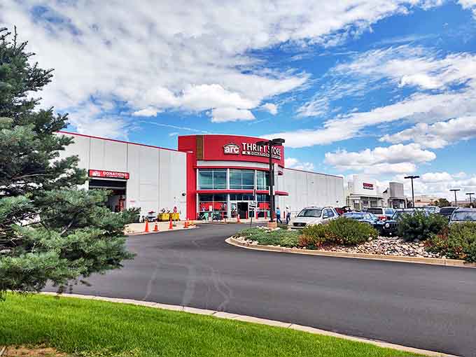 The distinctive red entrance of arc Thrift Store stands like a beacon of bargain hope against Colorado's brilliant blue sky, promising treasures within.