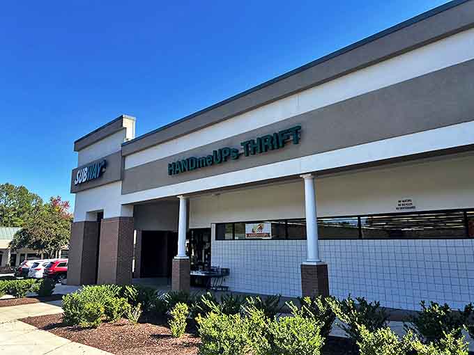 HandmeUPs Thrift sits unassumingly in a strip mall, like a treasure chest disguised as an ordinary box. The teal signage promises adventures in bargain hunting.