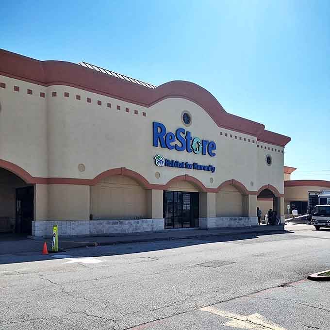 The distinctive cream and coral exterior of ReStore beckons like a treasure chest waiting to be opened. Blue signage pops against the Southwestern-inspired architecture, promising affordable home transformation adventures inside.