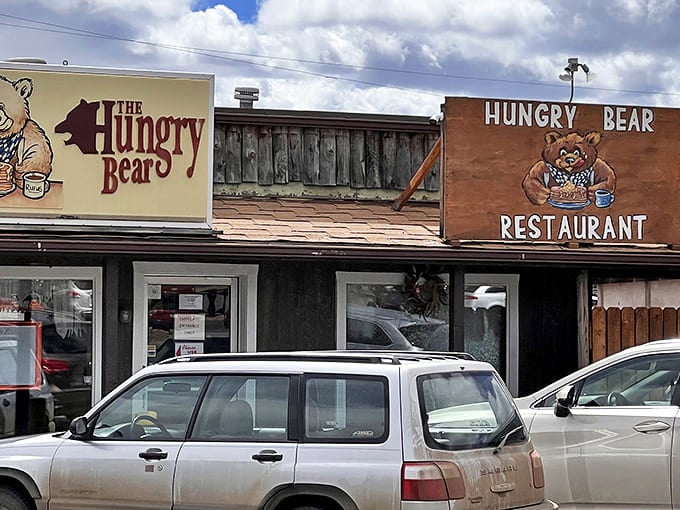Dual signs welcome hungry visitors to Woodland Park's beloved bear-themed eatery, where comfort food and value await beneath Colorado skies.