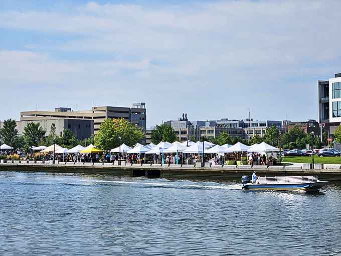 Shoppers browse vendor tents along the Providence River while a boat glides by—the perfect Sunday afternoon treasure hunt.